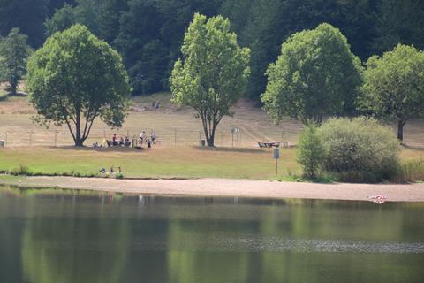 Badegäste sitzen am Marbach-Stausee auf dem Trockenen